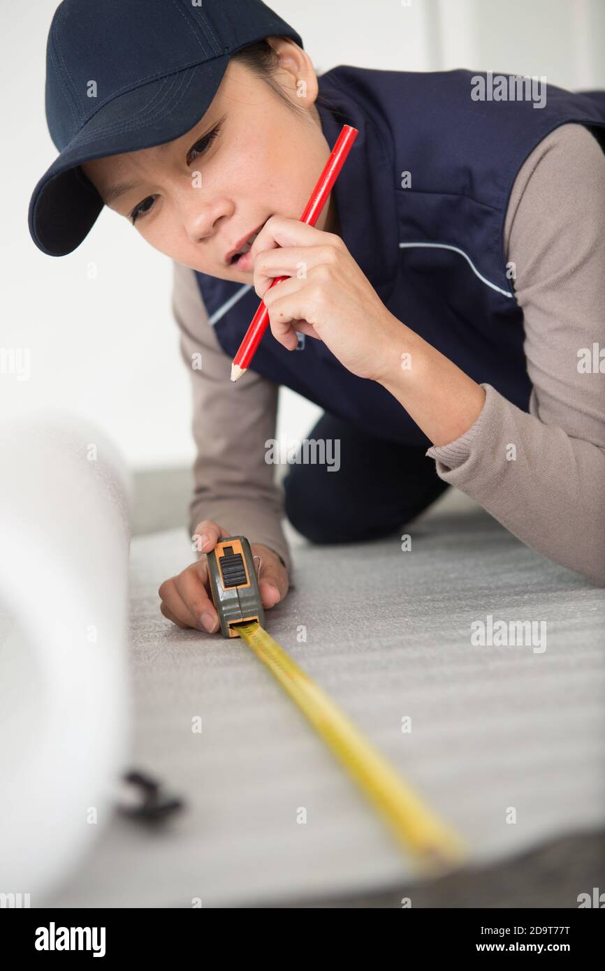 thinking woman with ruler measuring wallpaper at home Stock Photo - Alamy