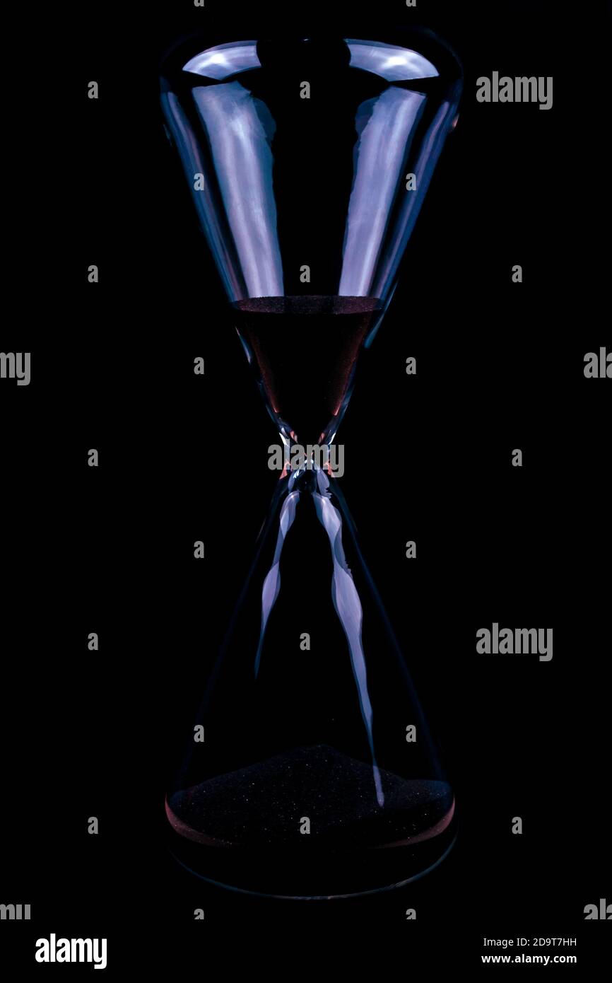 glass hourglass time concept on a black backdrop. Countdown timing ...