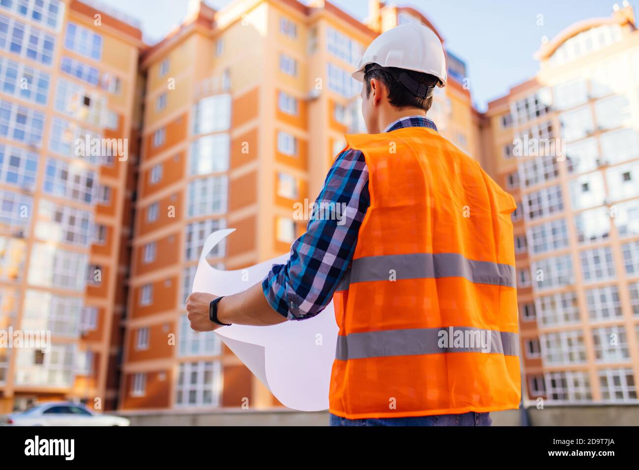 Engineer builder wearing safety vest with blueprint at construction ...