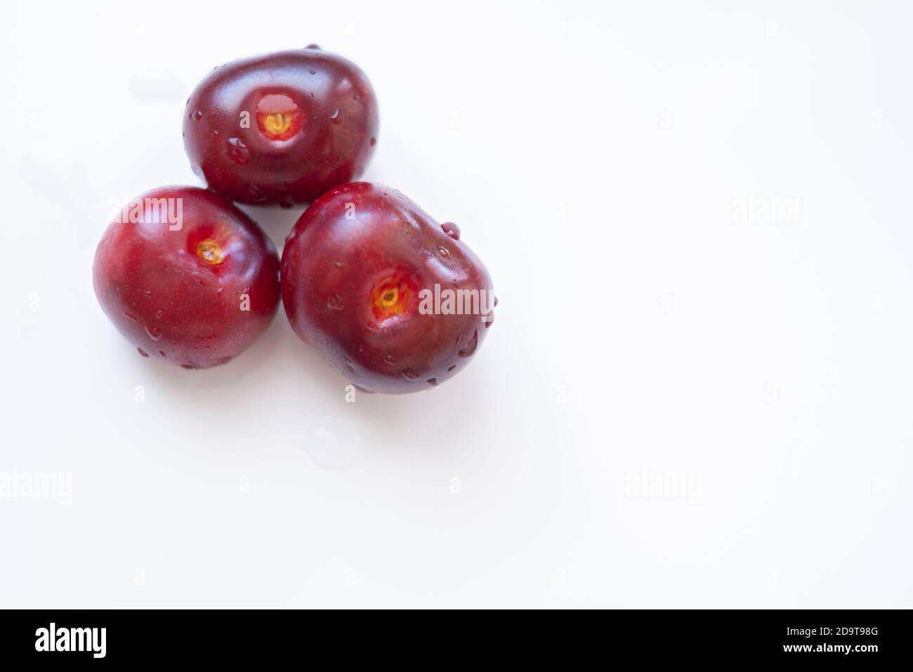 three fresh cherries on a white background with a few drops of water on ...