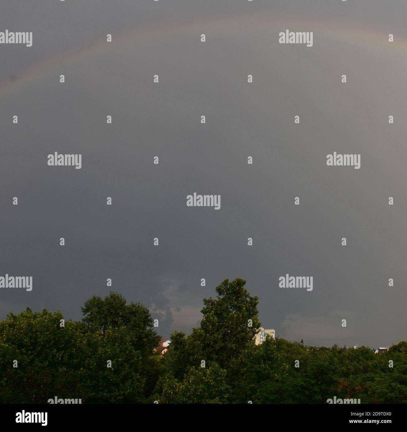 A rainbow appeared across the gray and cloudy sky Stock Photo - Alamy