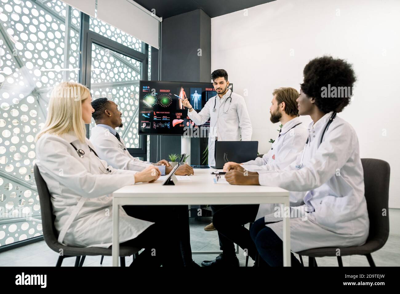Handsome young Indian man doctor consulting team of multiracial ...