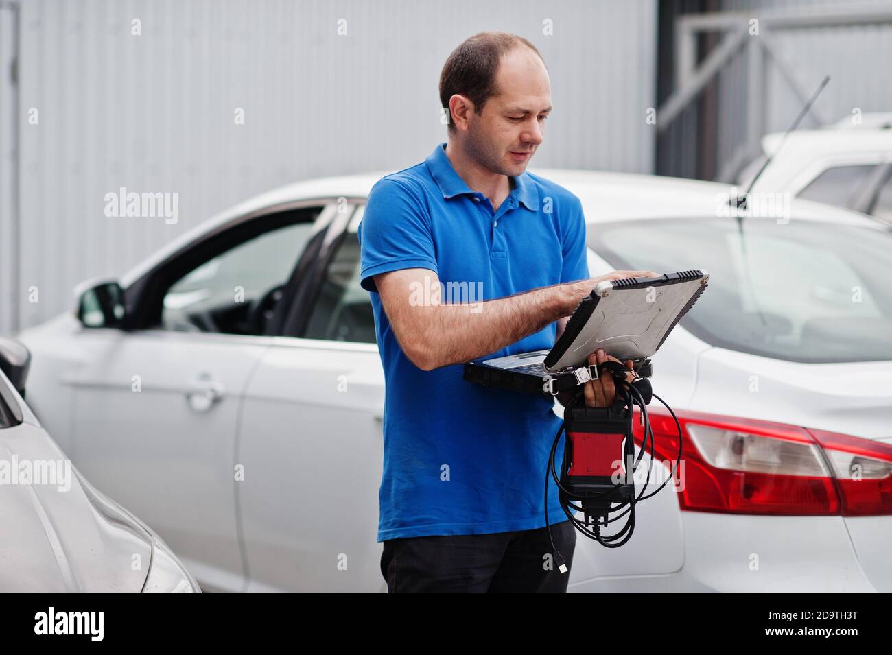 Car repair and maintenance theme. Electric mechanic in uniform working in auto service, making ...