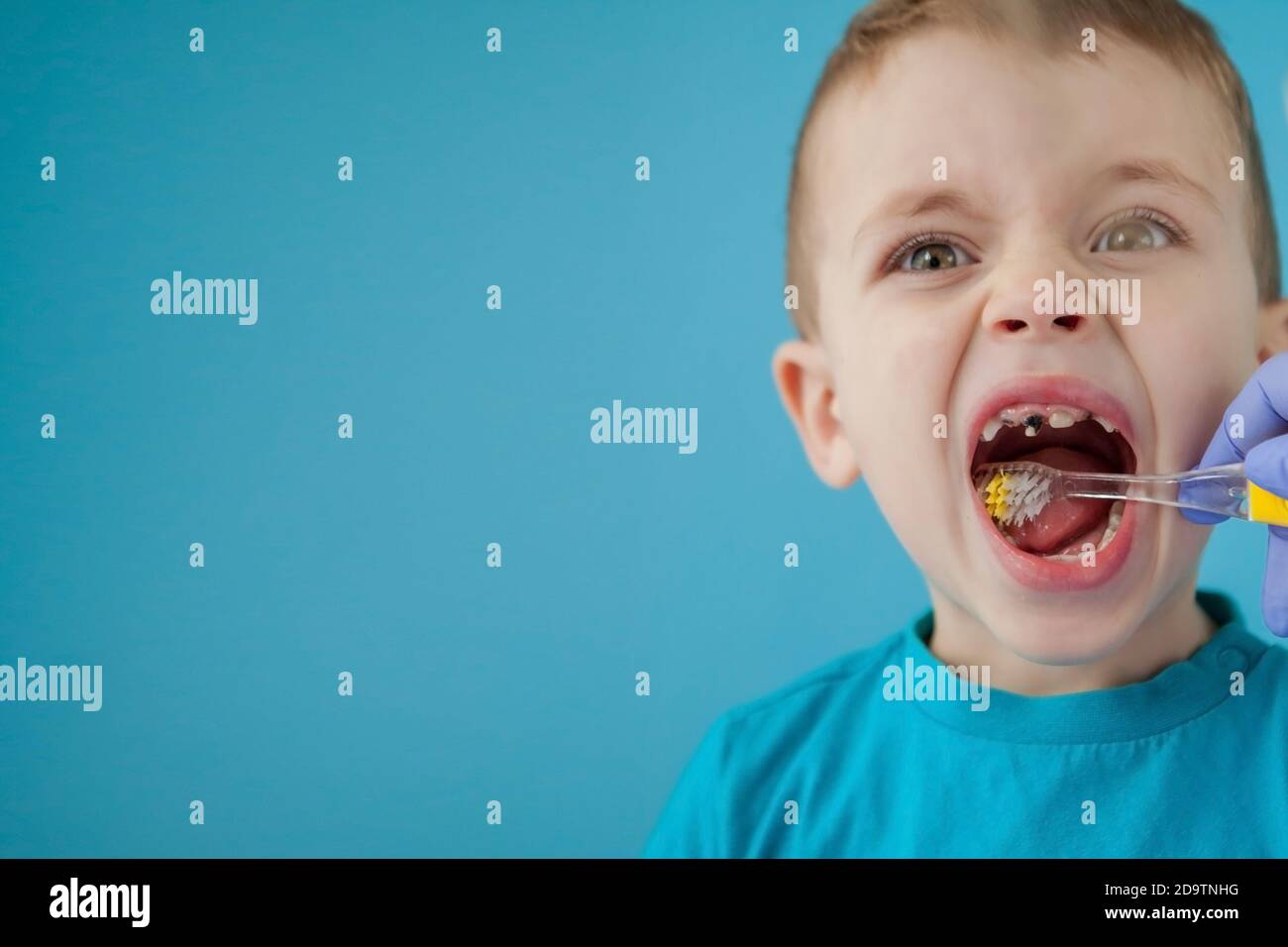 Little cute boy brushing his teeth on blue background Stock Photo - Alamy
