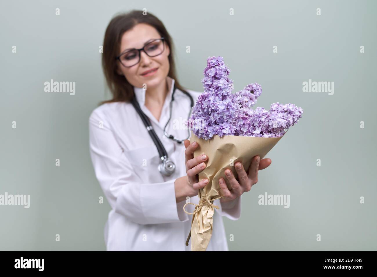 Bouquet of lilac flowers in the hands of female doctor with stethoscope ...