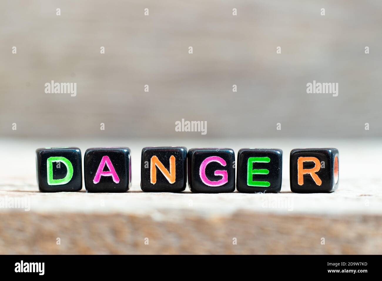 Black bead with color letter in word danger on wood background Stock ...