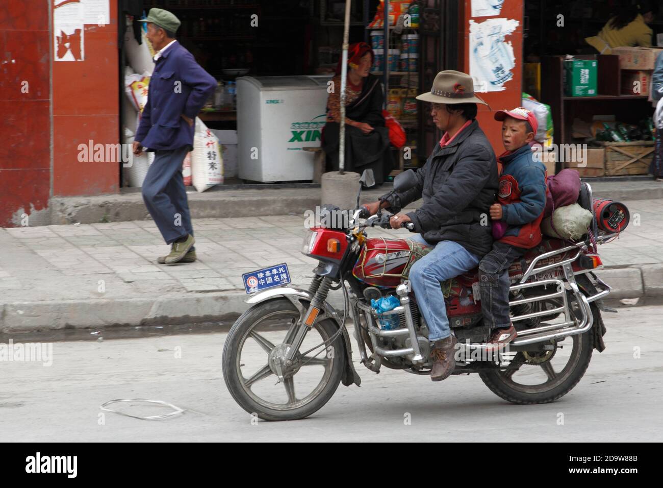 Tibetan man and boy on a motorcycle, main street, Bamei, west Sichuan ...