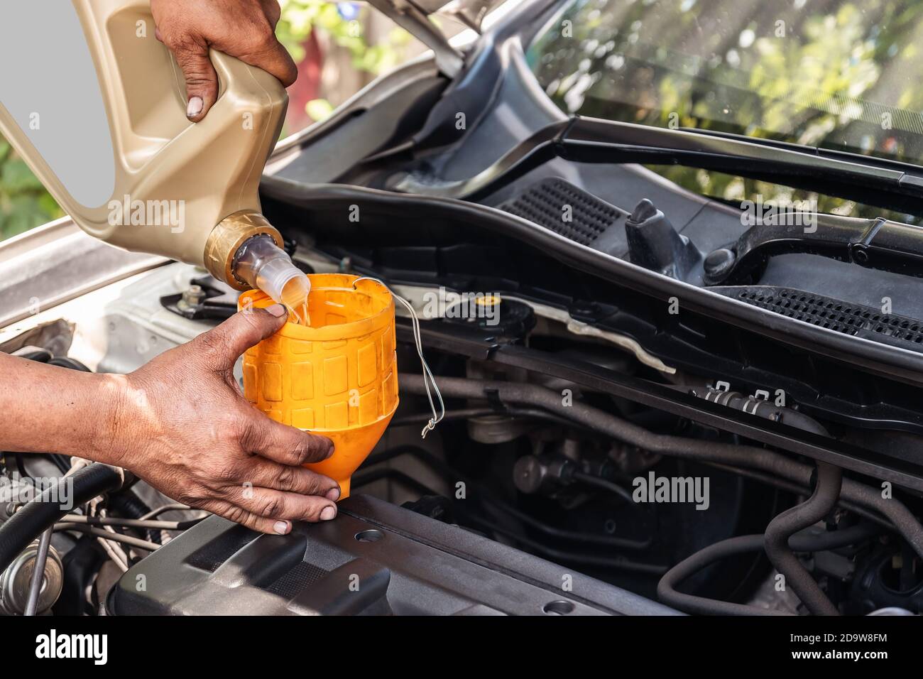 Car mechanic is adding oil to the engine, Automotive industry and ...
