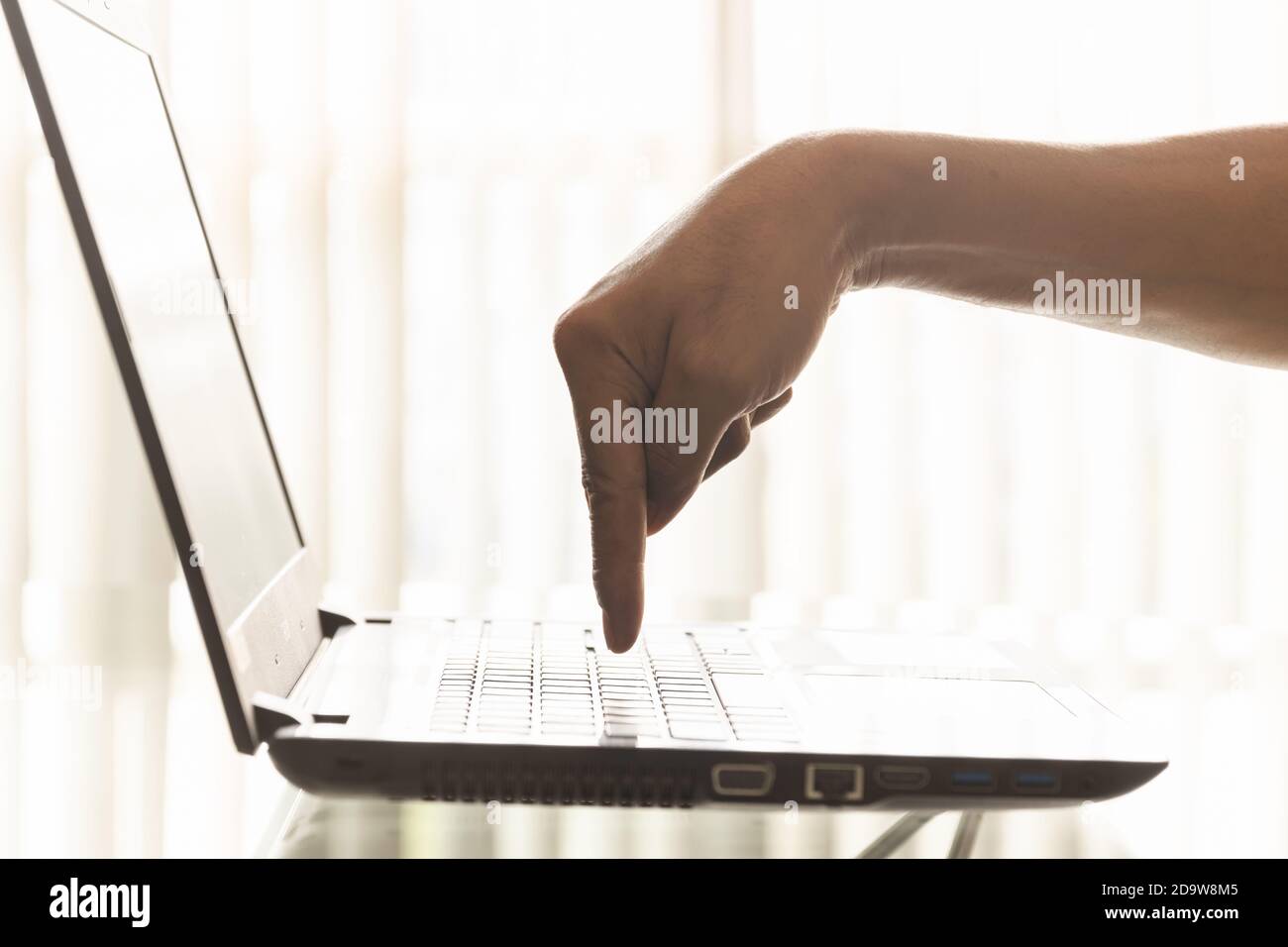 A businessman's finger is pressing down on the laptop's keyboard button ...