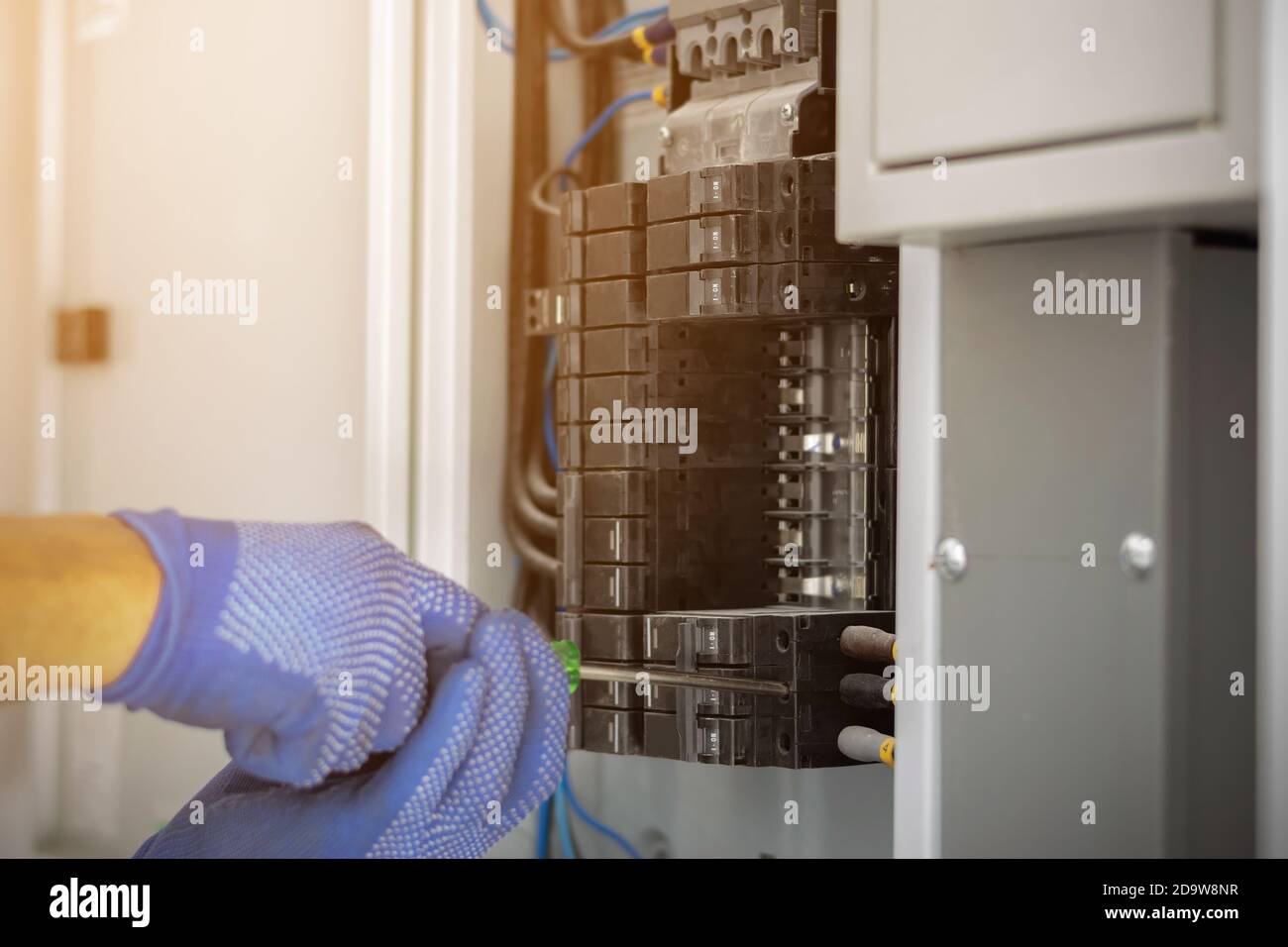Electrician is using a screwdriver to install the breaker in the ...