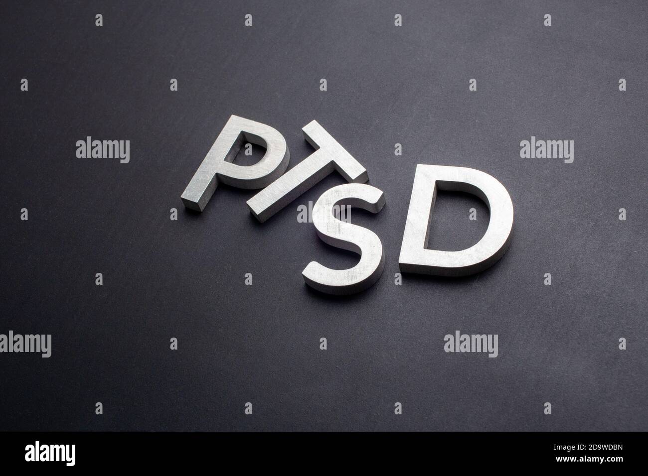 the word PTSD laid with silver metal letters on flat black background ...