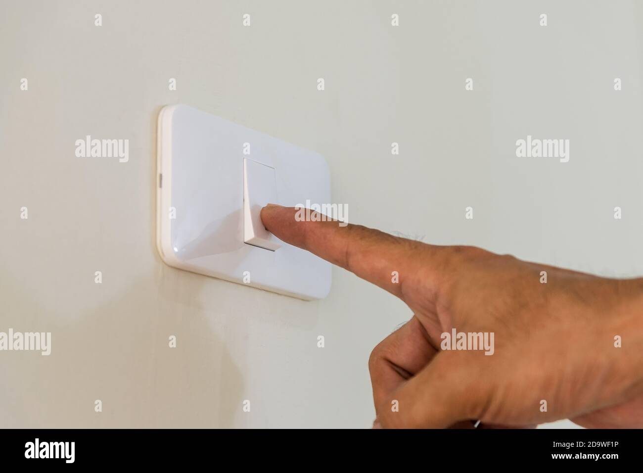 Men's fingers are extended to open the light switch on the wall Stock ...