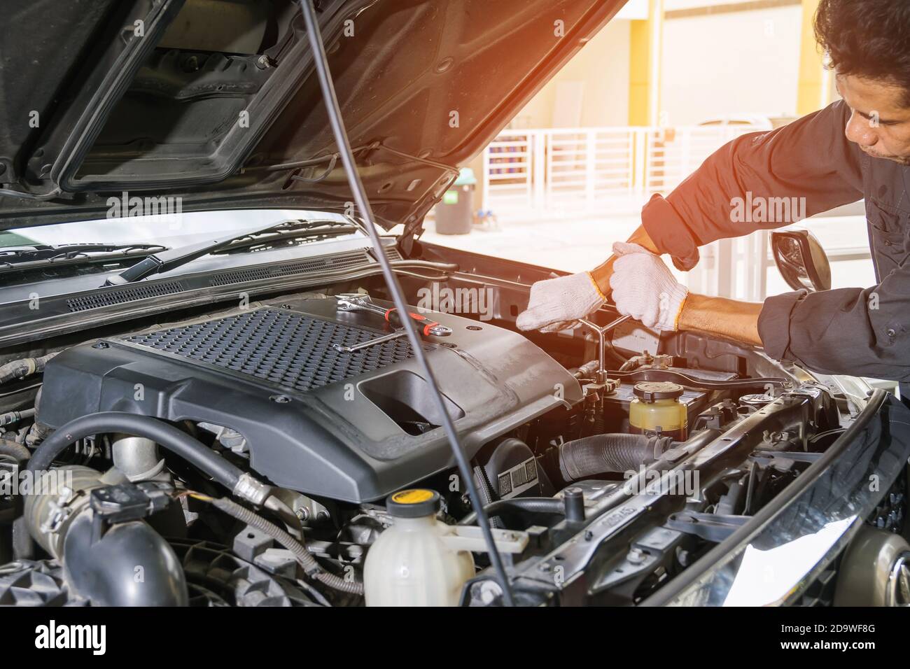 Car mechanic in grey uniform are using a wrench nut at the engine of ...
