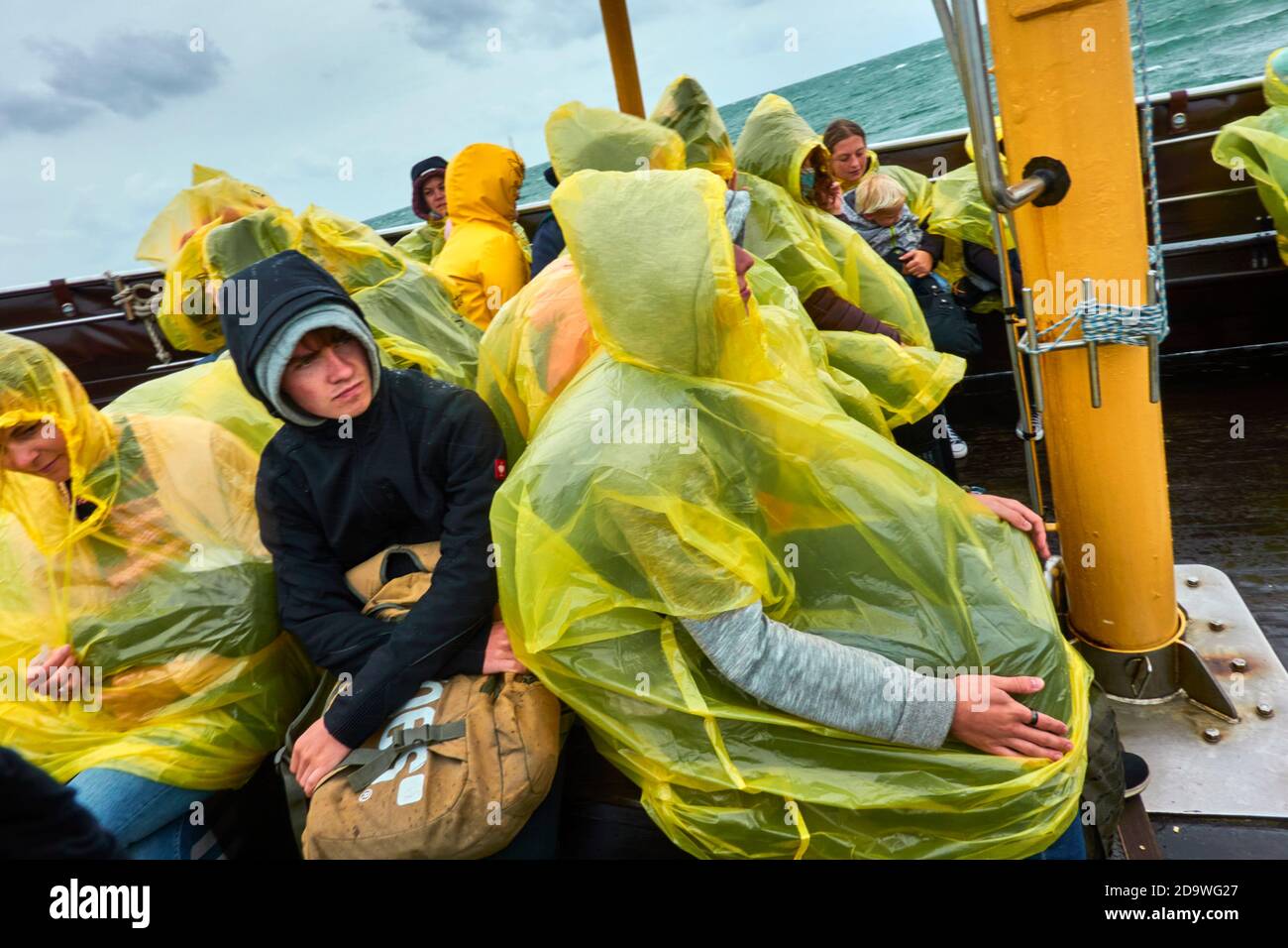 Sylt, Germany, September 3., 2020: Tourists in thin yellow rain capes ...