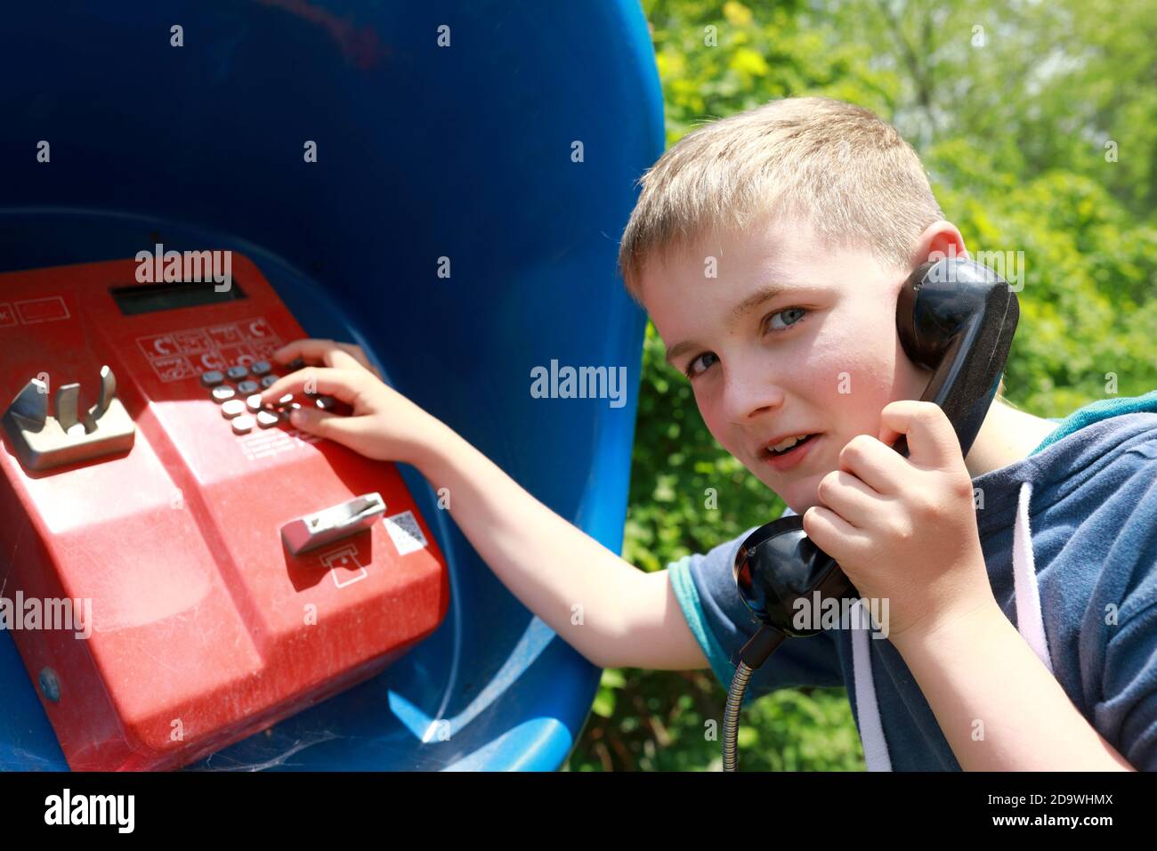 Boy dials number on street fixed telephone in summer Stock Photo - Alamy