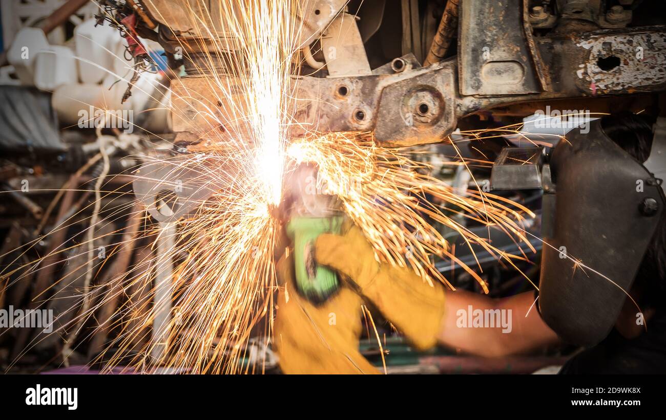 Fire flames are caused by a car mechanic using an electric grinder to ...