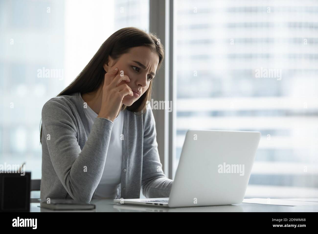 Frowning woman employee looking at screen unable to find decision Stock ...