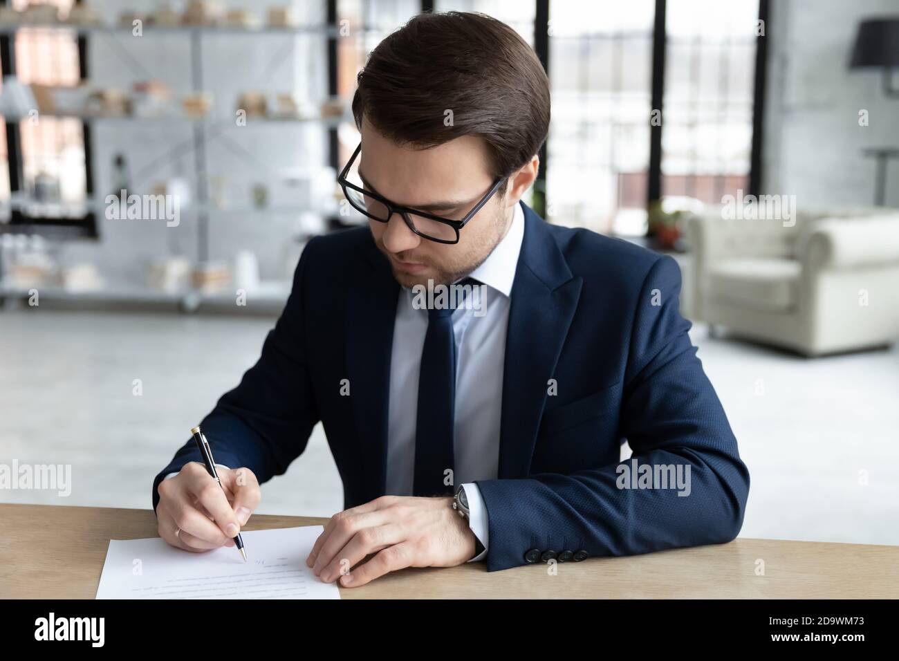 Focused young businessman putting signature on documents Stock Photo ...