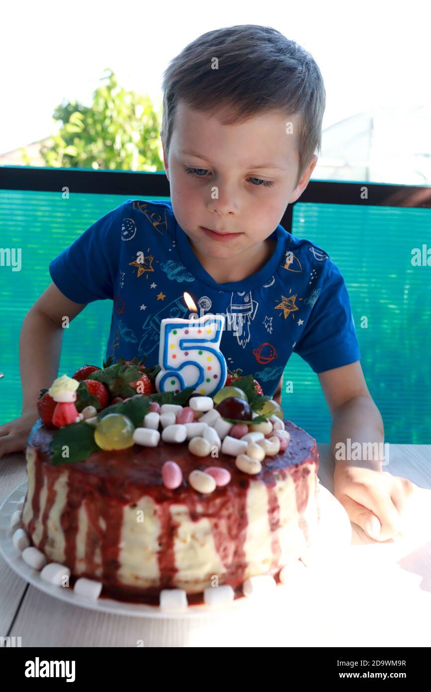 Birthday child blows out candles on cake in backyard Stock Photo - Alamy