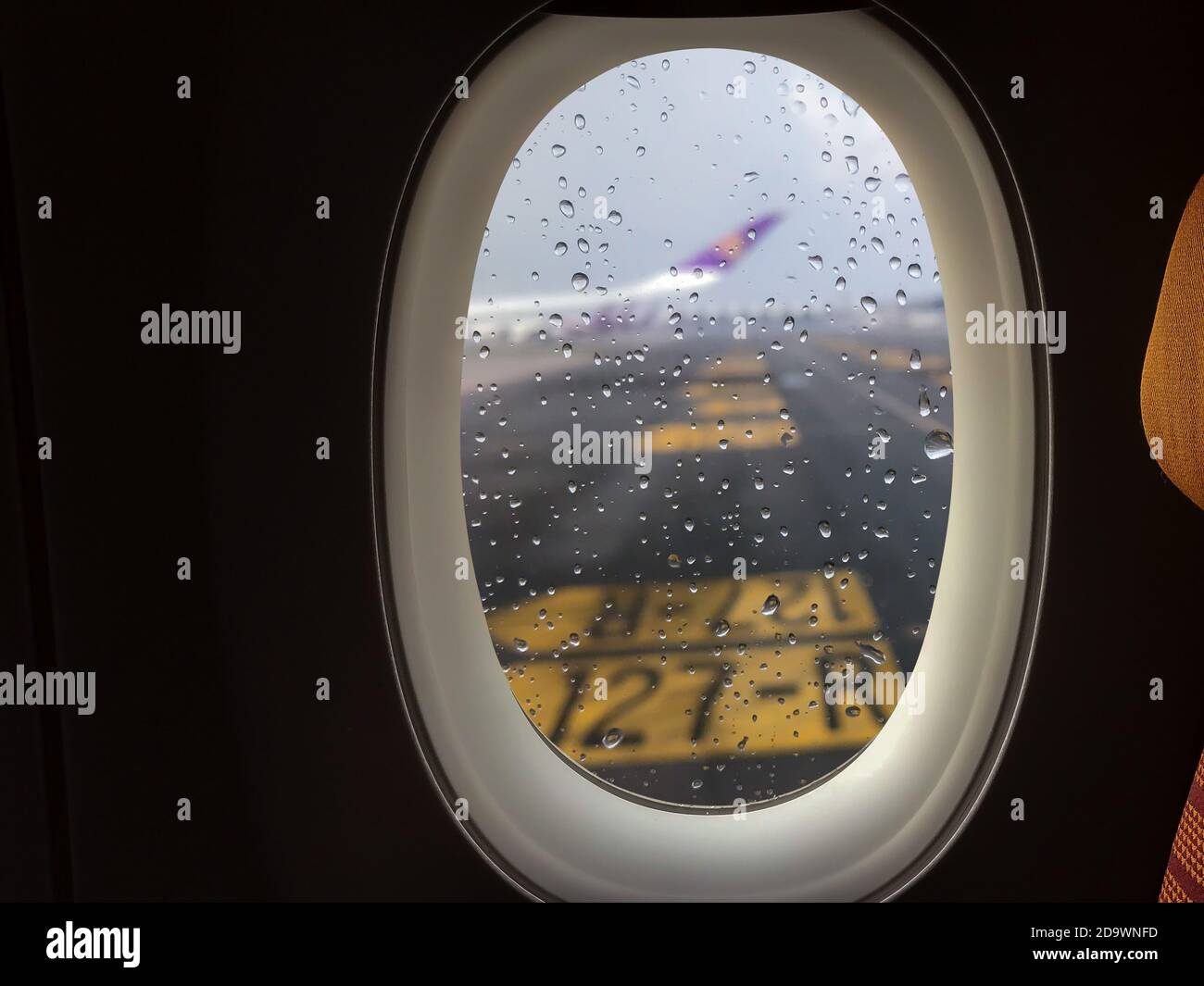 The rain drops on the glass outside of the passenger plane window that ...