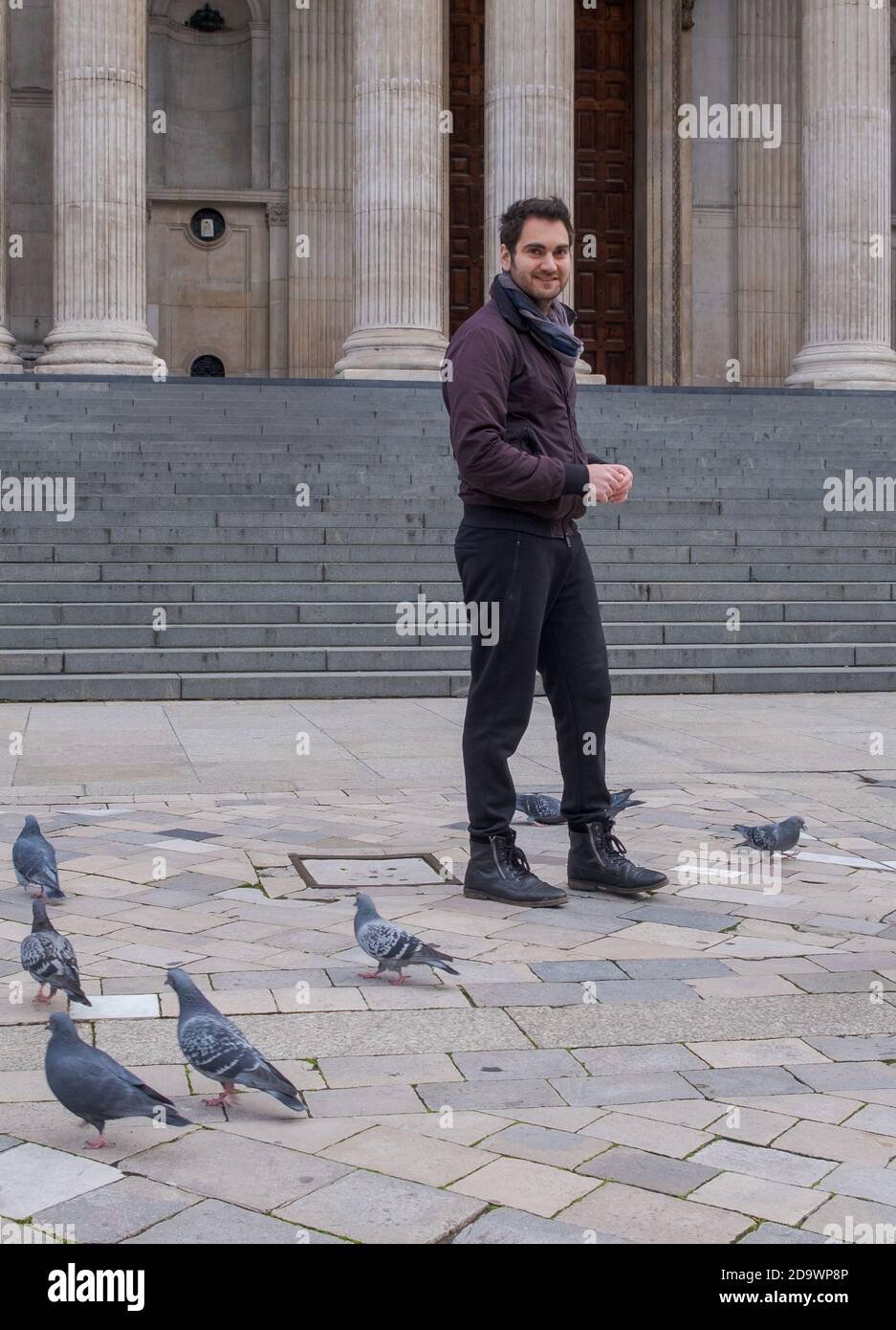 A man standing at St Paul’s Cathedral west front smiling. Pigeons on ...