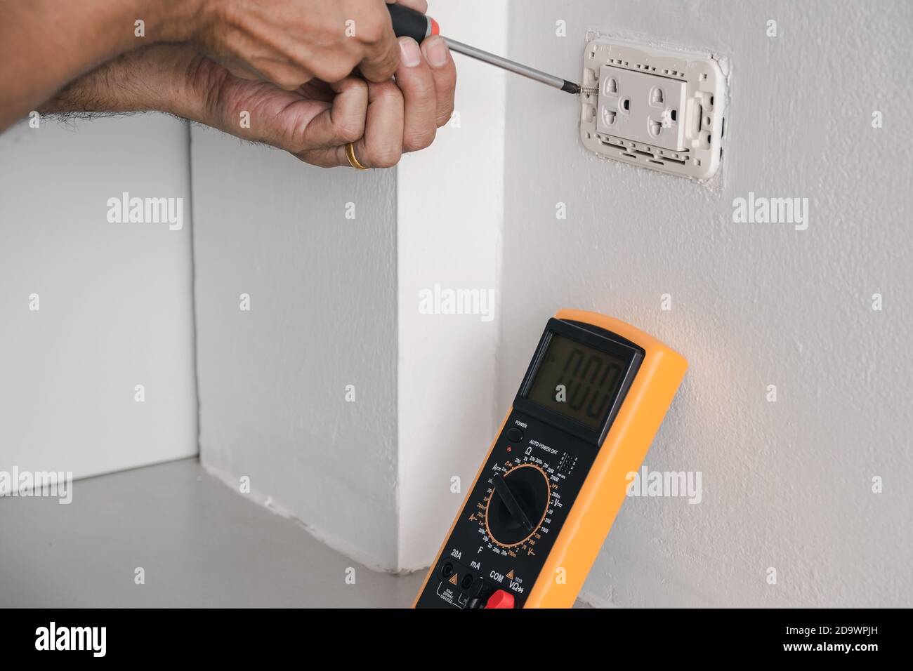 The electrician is using a screwdriver to attach the power cord to the ...