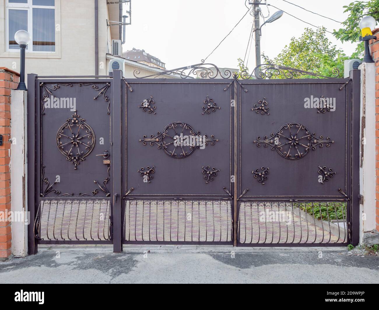 Dark metal gates and a wicket with bars and a forged pattern near the ...