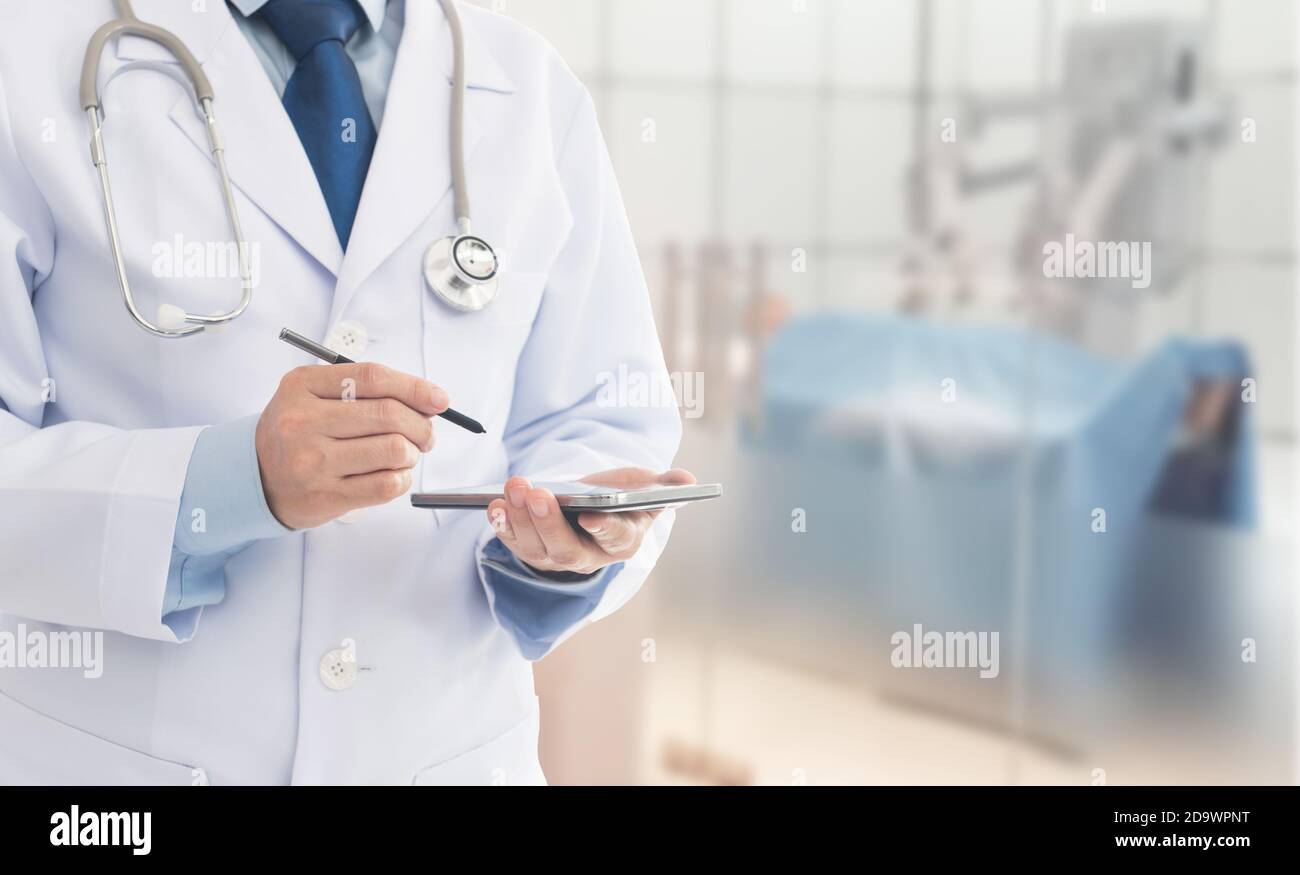 Doctor using a mobile phone with surgery room at the background ...
