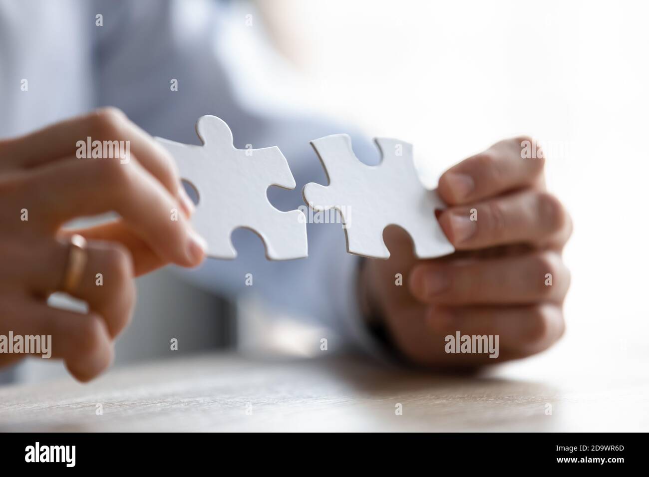 Close up young entrepreneur putting different parts of puzzles together ...