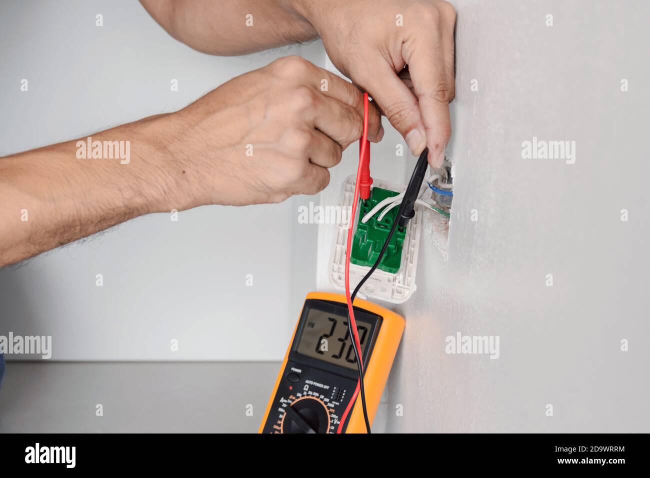 Electrician is using a digital meter to measure the voltage at the ...