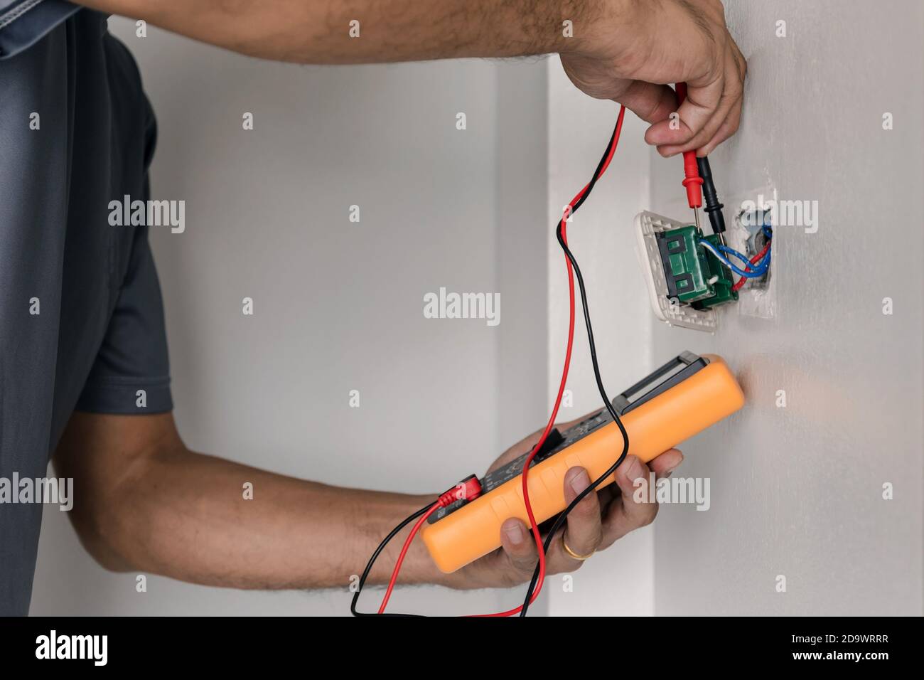 Electrician is using a digital meter to measure the voltage at the ...