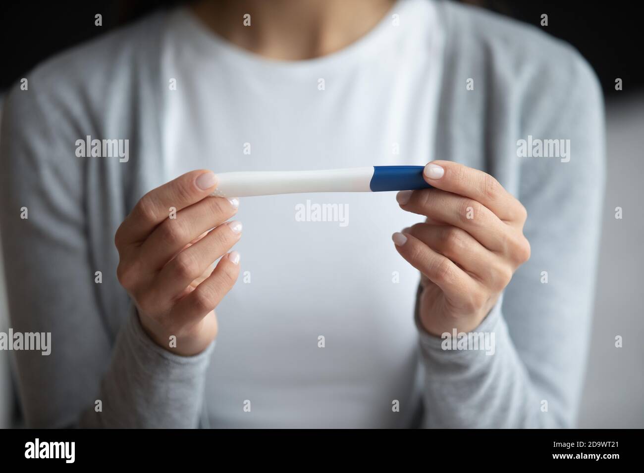 Young female holding midstream rapid pregnancy test looking at result ...
