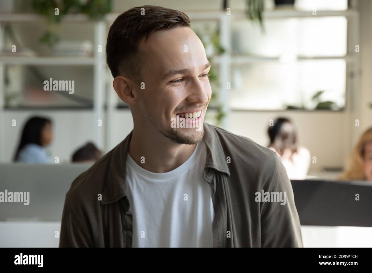 Positive male office worker smiling looking aside having good workday ...