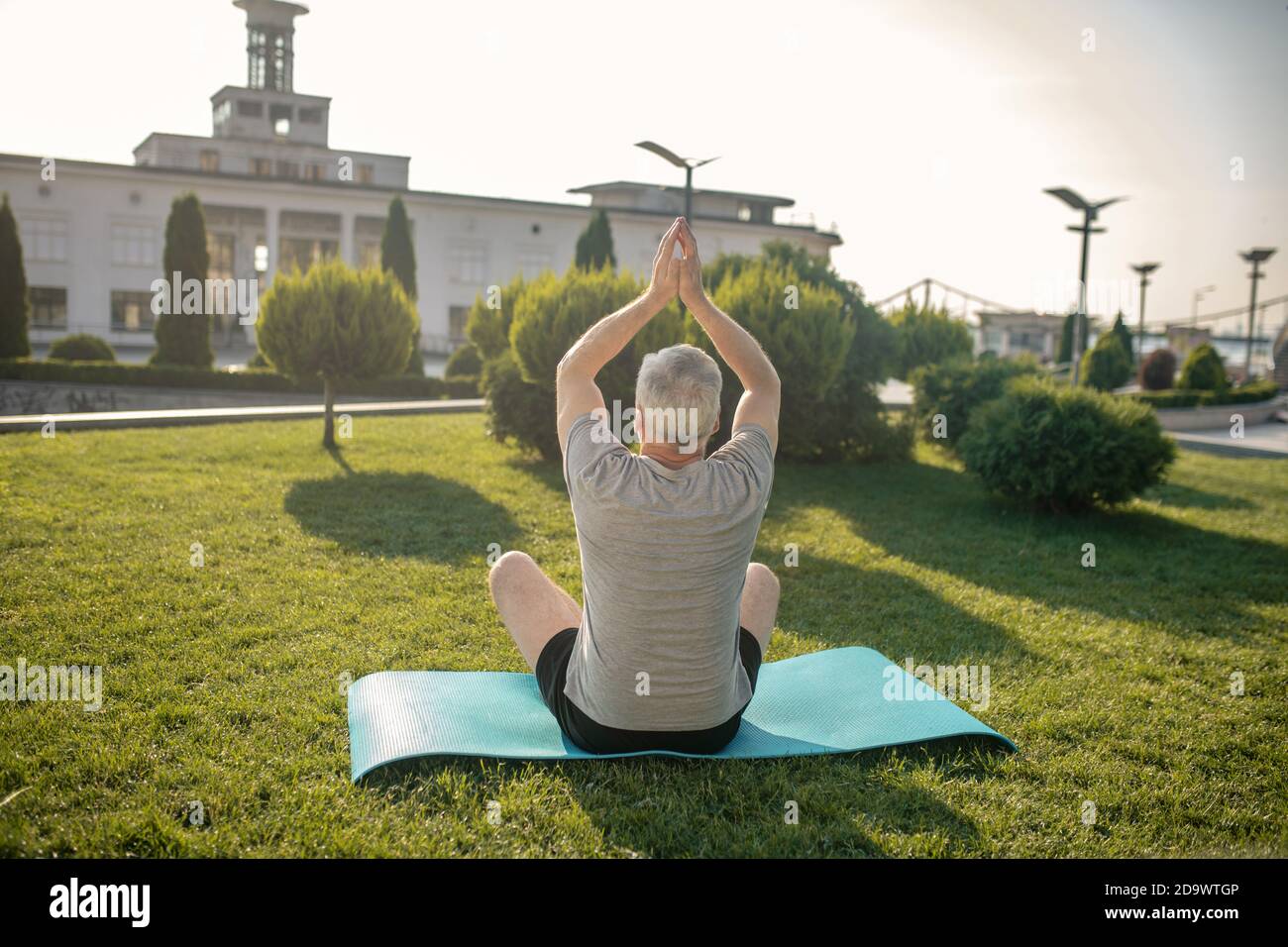 Peaceful meditation. Back view of grey-haired man practicing yoga ...