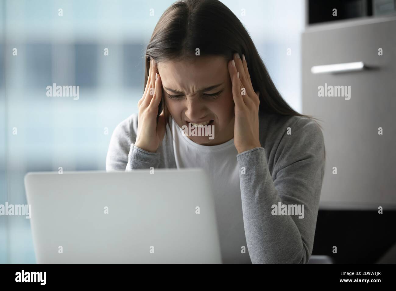 Nervous lady office worker hugging head in panic before laptop Stock ...