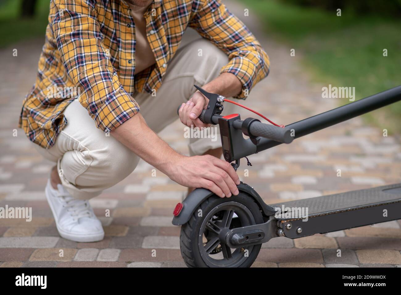 Scooter. Man sitting on his hunkers and fixing his scooter Stock Photo ...