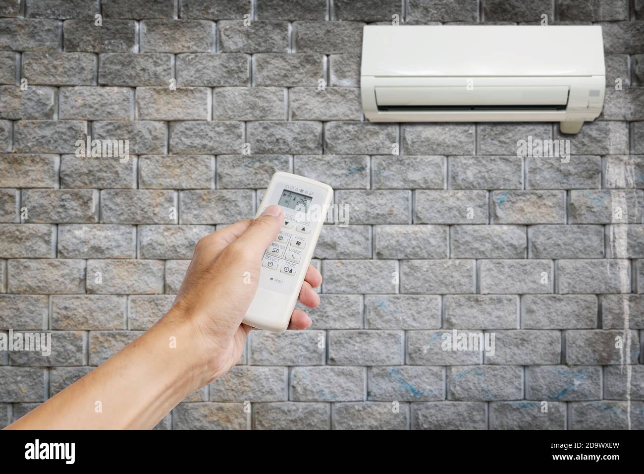 Hand holding the remote control to control the air conditioning on the ...