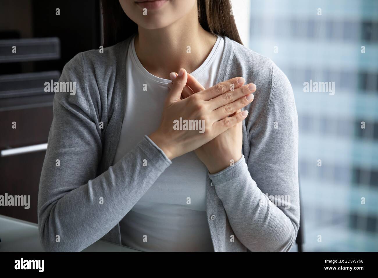 Young woman hands folded on chest expressing heartfelt thank you Stock ...