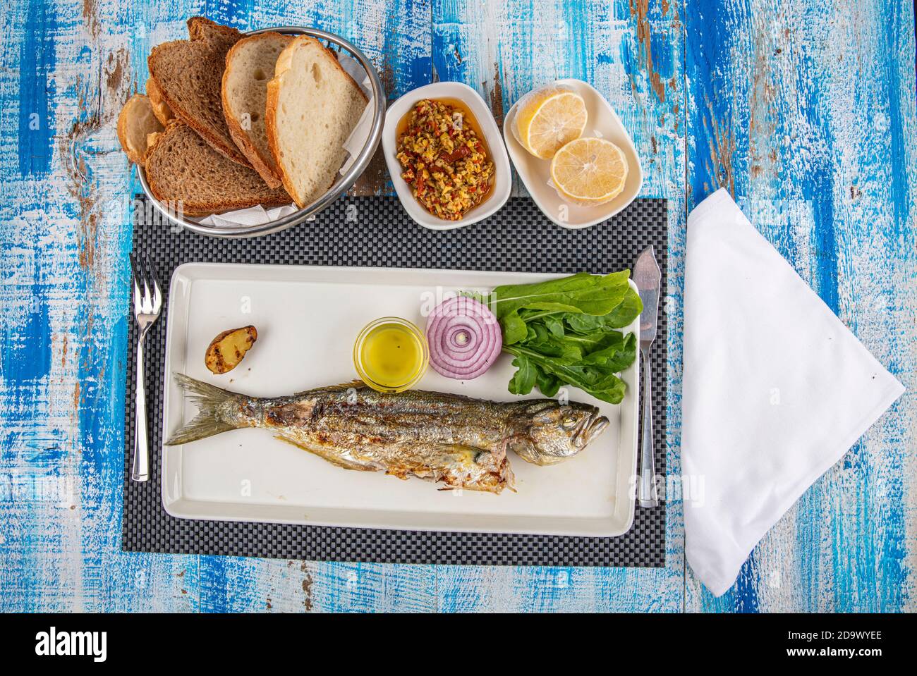 Grilled bluefish fish platter. Bluefish and appetizers in white plate ...
