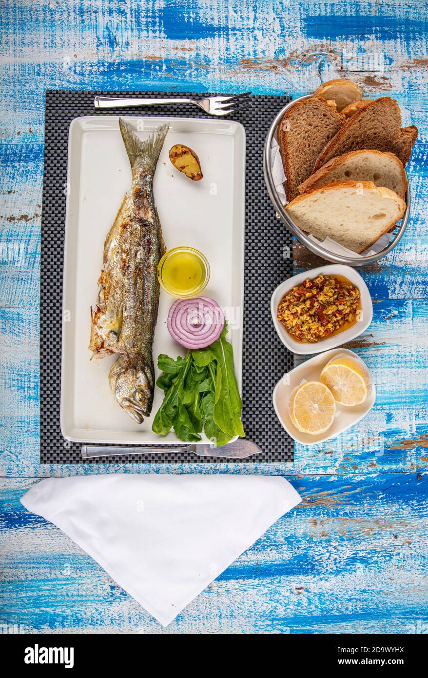 Grilled bluefish fish platter. Bluefish and appetizers in white plate ...