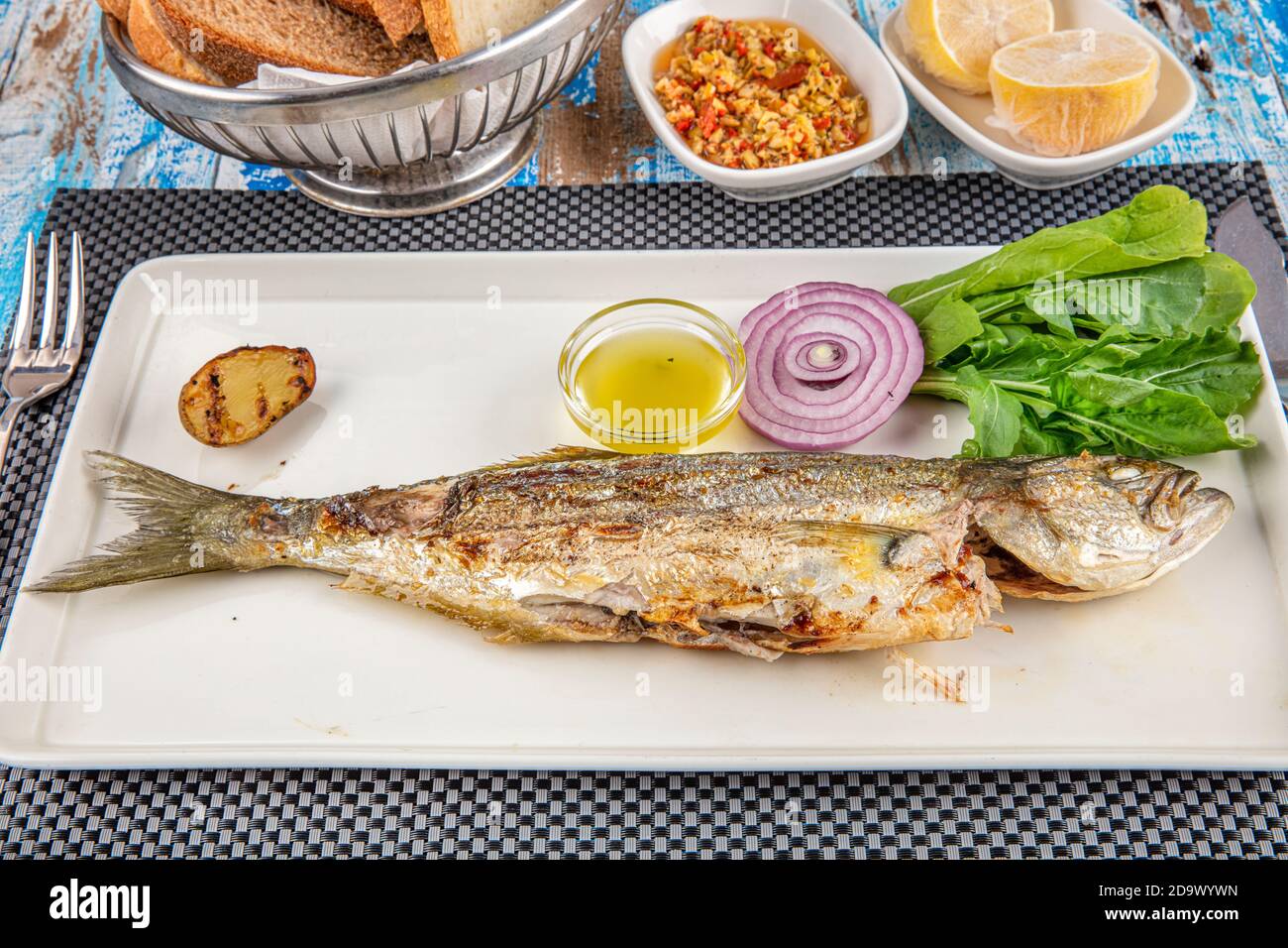 Grilled bluefish fish platter. Bluefish and appetizers in white plate ...
