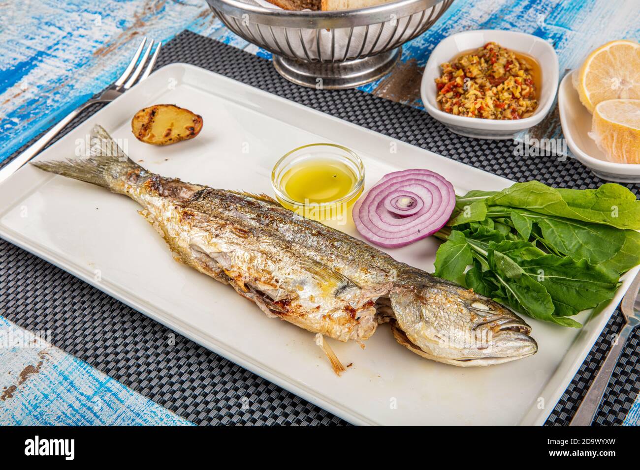 Grilled bluefish fish platter. Bluefish and appetizers in white plate ...