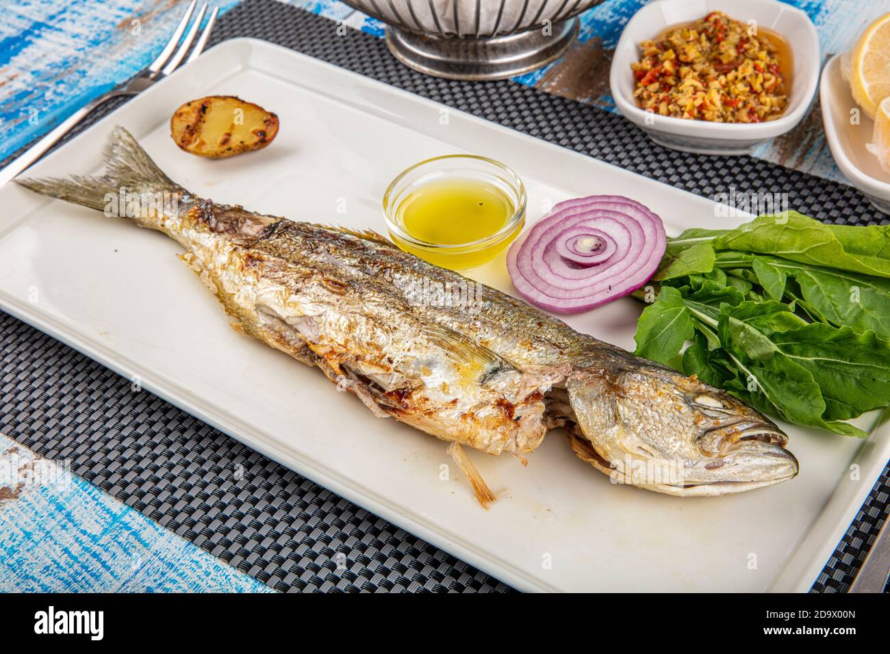 Grilled bluefish fish platter. Bluefish and appetizers in white plate ...