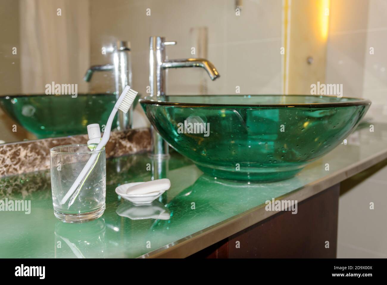Toothbrush and toothpaste in a glass placed in front of the mirror near ...