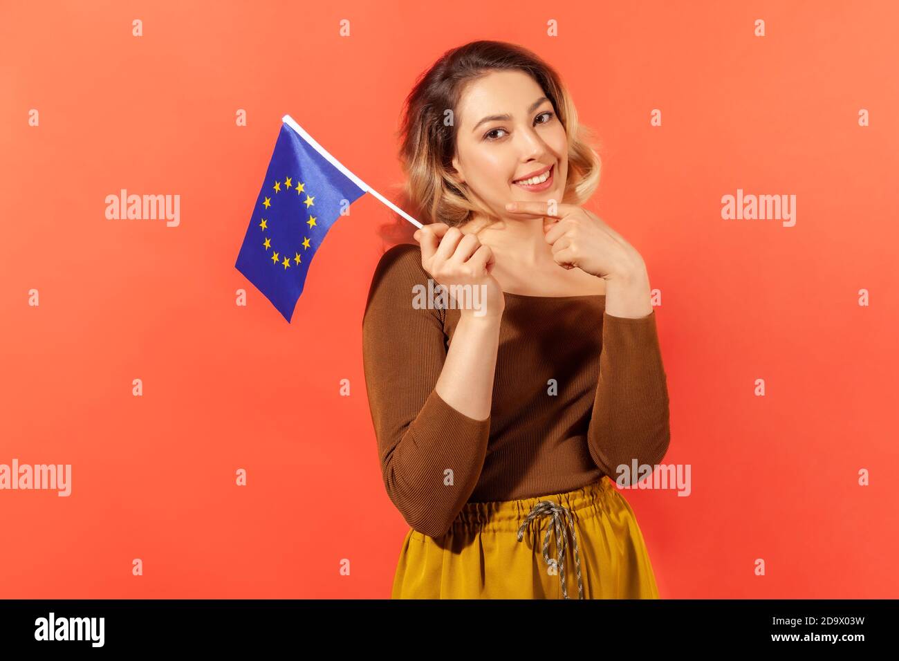 Happy smiling woman pointing finger at europe union blue flag with ...