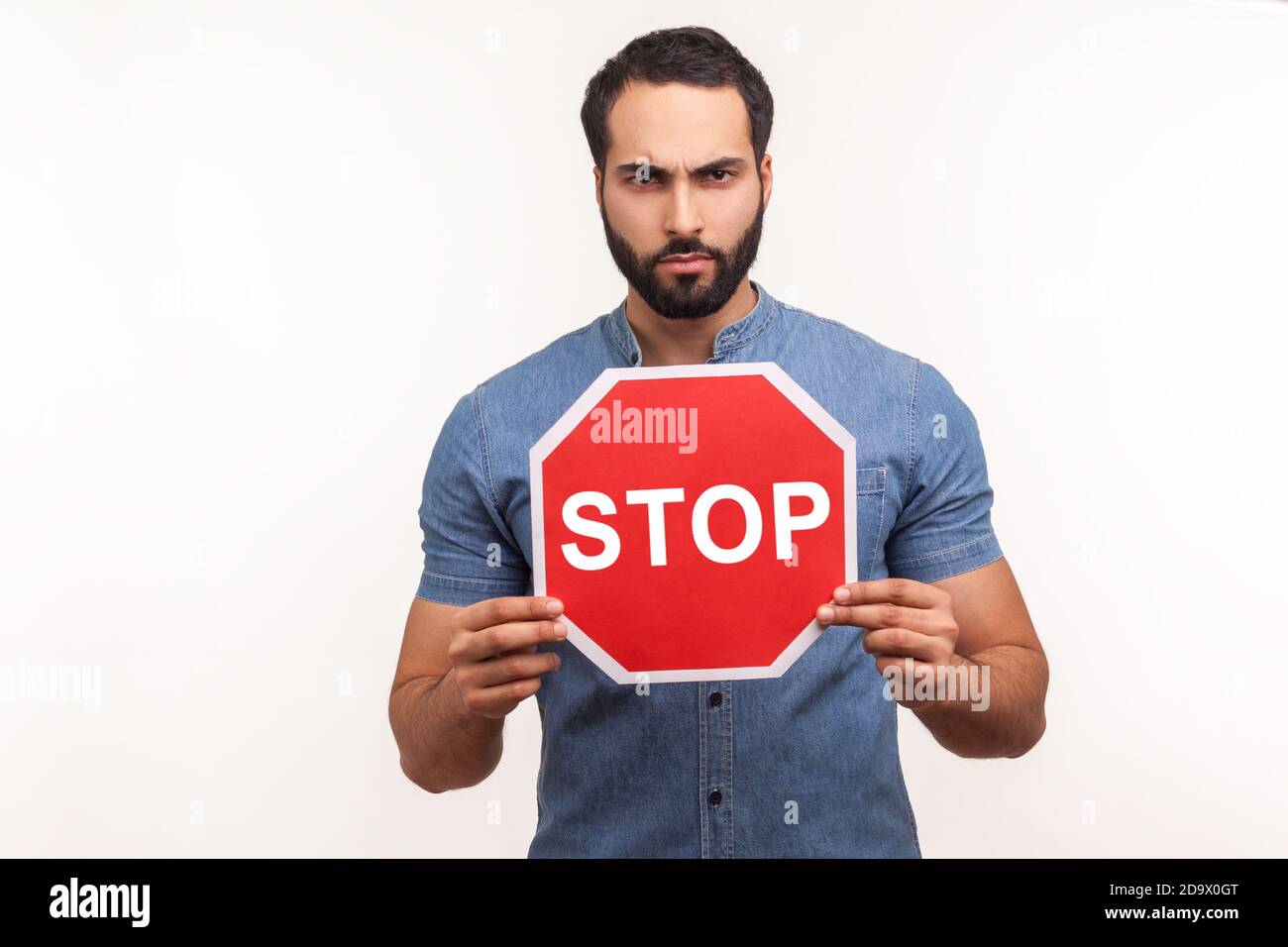 Concerned nervous bearded man in blue shirt holding red stop sign ...