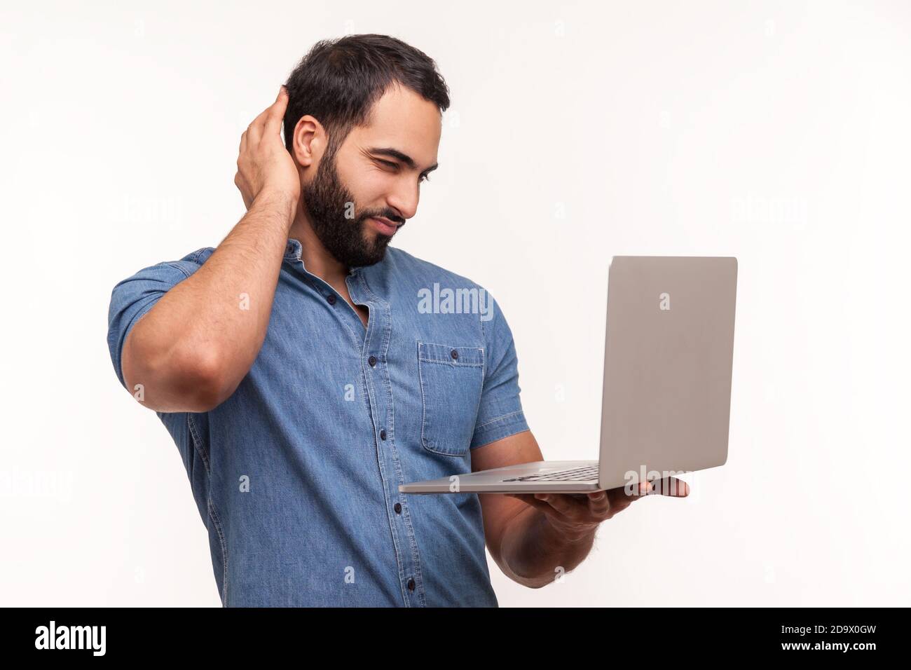 Thoughtful bearded man looking at laptop display rubbing his back of ...