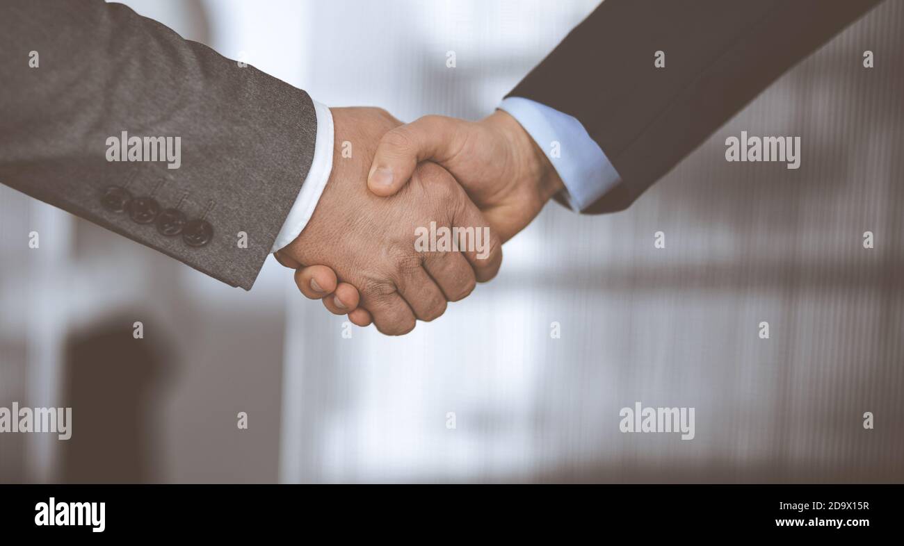 Business people in office suits standing and shaking hands, close-up ...