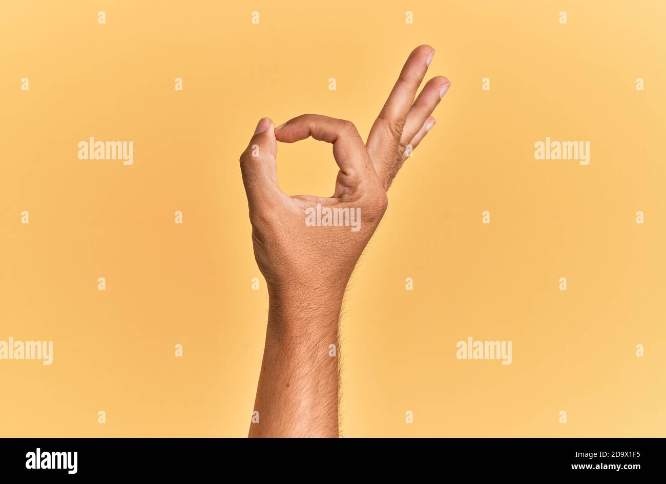 Arm and hand of caucasian man over yellow isolated background gesturing ...