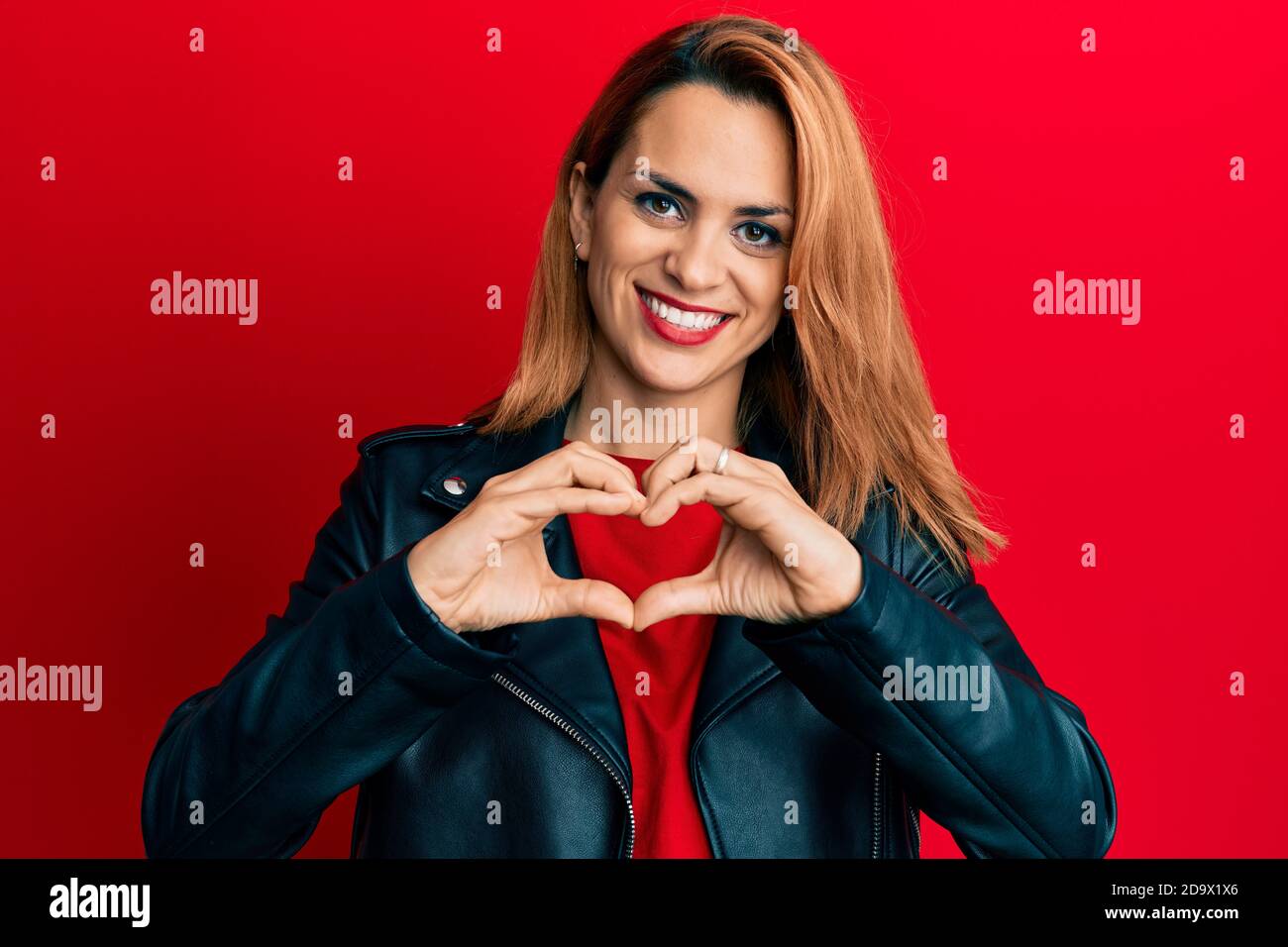 Hispanic young woman wearing black leather jacket smiling in love doing ...